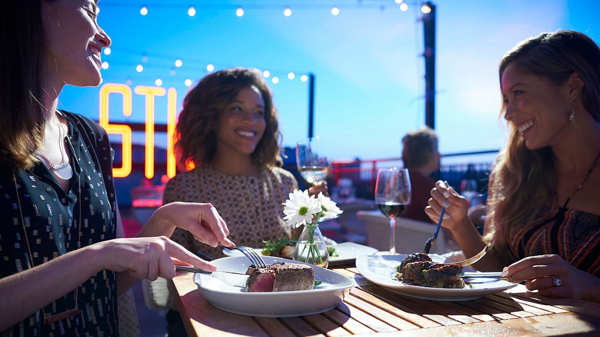 3 women eating dinner on the rooftop deck of STK restaurant at Disney ...